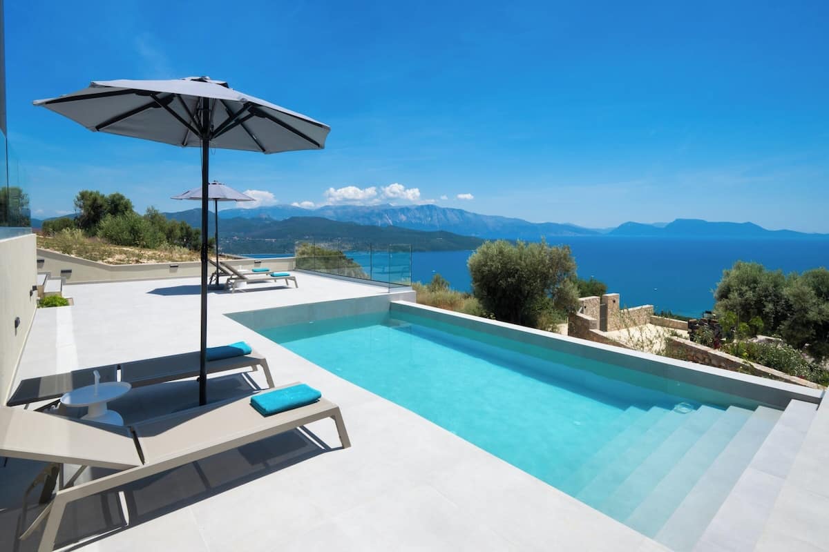 Uma área moderna com piscina ao ar livre, com vista para o mar e montanhas.