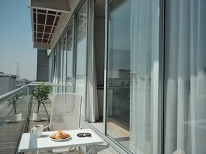 Uma varanda com mesa, cadeira, um prato de comida, xícara e um par de óculos de sol.