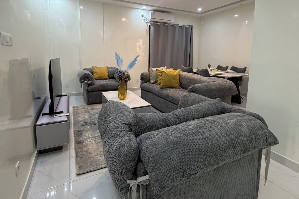 Uma sala de estar moderna com um conjunto de sofá, uma mesa de centro e uma televisão.