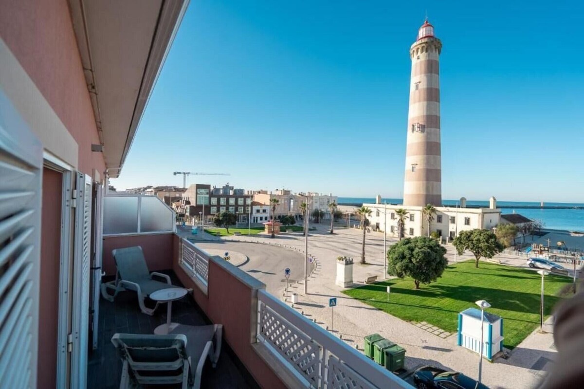 Uma varanda com vista para uma cidade costeira, um farol e um céu claro.
