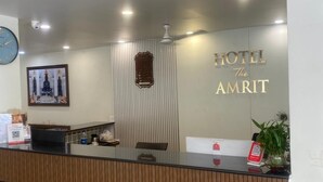Balcão de recepção de hotel com um relógio, um quadro emoldurado e uma placa que diz 'HOTEL The AMRIT'.