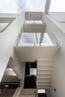 Interior com vários níveis, corrimão de vidro e escada.