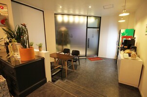 Um hall de hotel moderno com balcão de recepção, área de estar e porta de vidro que dá para um quarto.