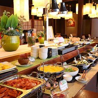Buffet com diversos pratos, uma planta em vaso e um aviso indicando opção vegetariana.