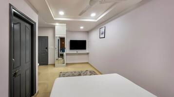 Um quarto moderno com uma cama, ventoinha no teto, iluminação embutida, televisão e um espelho.