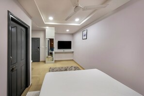 Um quarto moderno com uma cama, ventoinha no teto, iluminação embutida, televisão e um espelho.