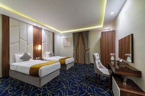 Quarto de hotel com duas camas, uma escrivaninha, uma cadeira e um espelho grande.