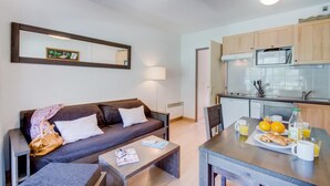 Uma sala de estar moderna com sofá, mesa de centro e um espaço para café da manhã com suco de laranja e croissants.