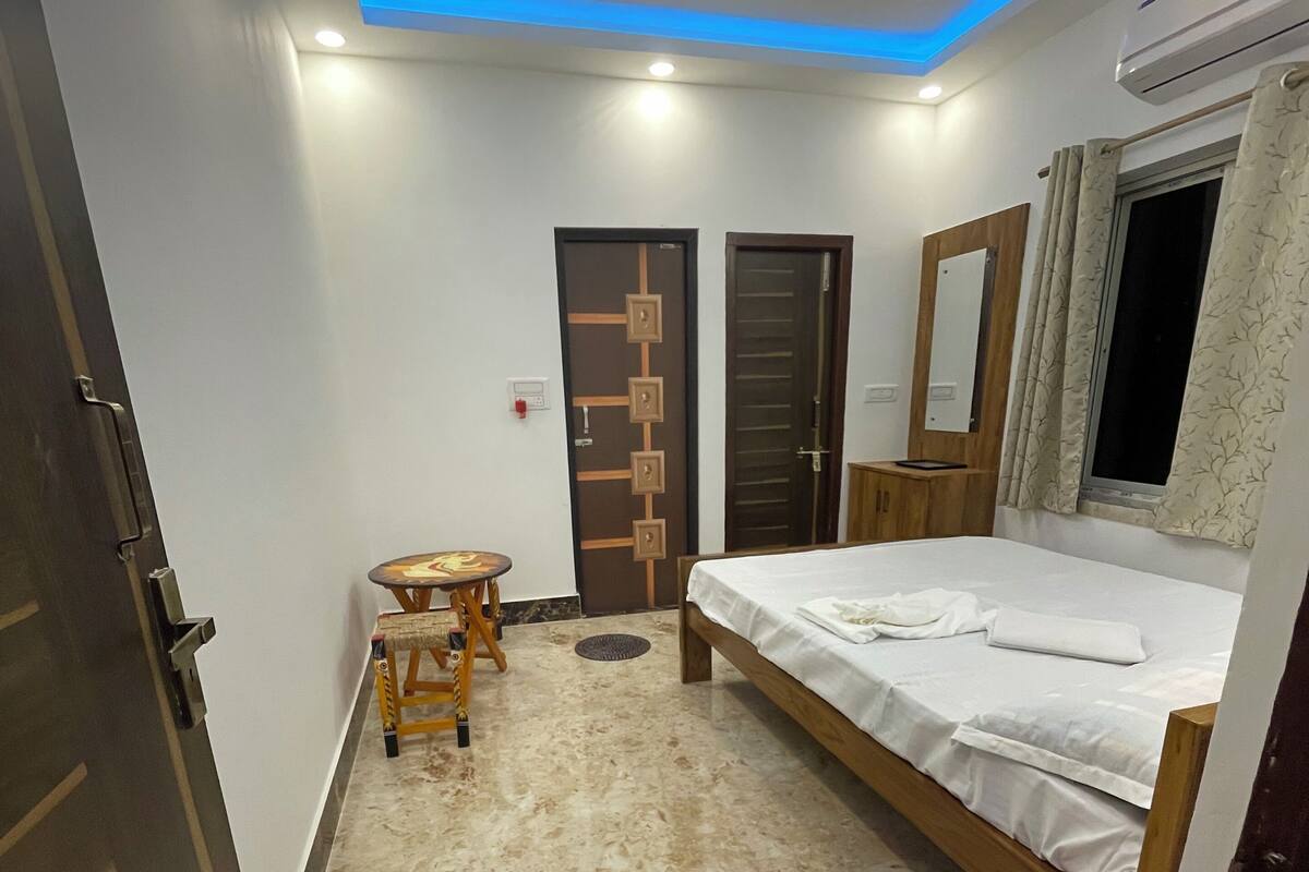 Quarto com cama, uma mesinha, espelho e ventilador de teto.