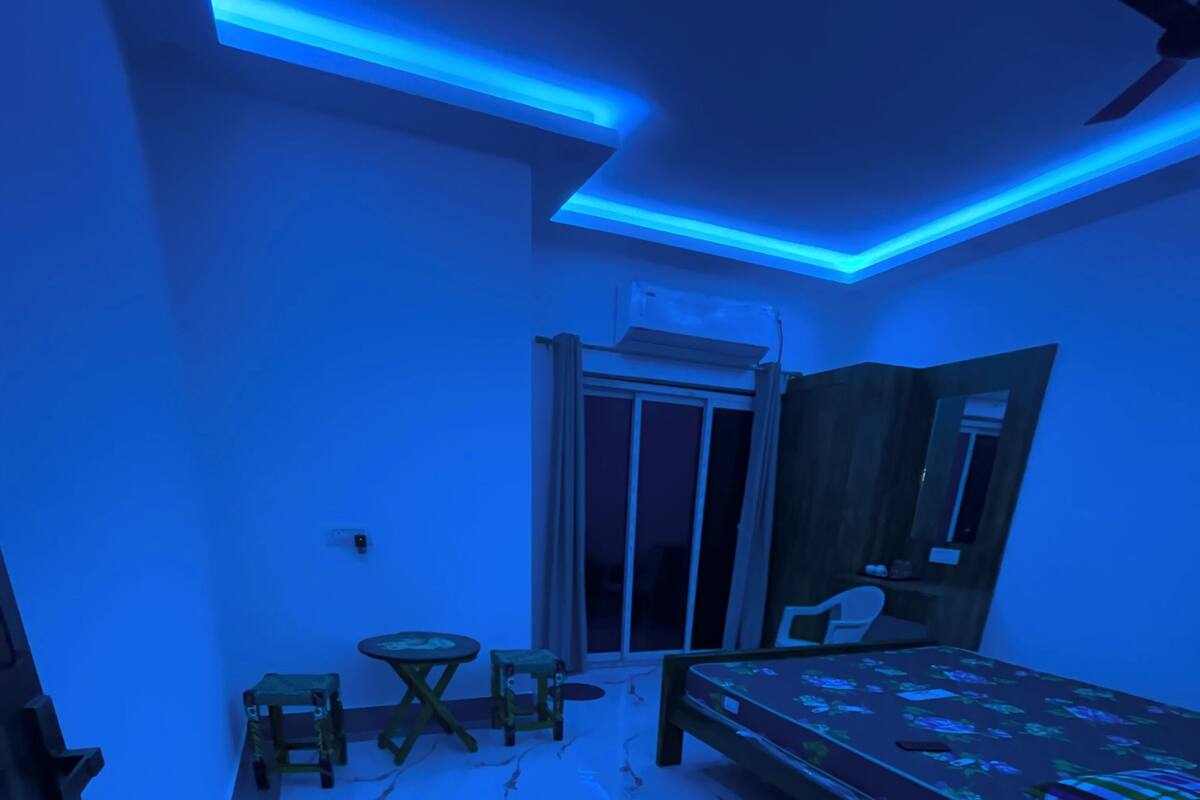 Quarto com cama, uma mesinha, uma cadeira e uma janela.