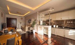Uma cozinha moderna com armários brancos, painel de backsplash de mármore e uma área de jantar com mesa e cadeiras de madeira.