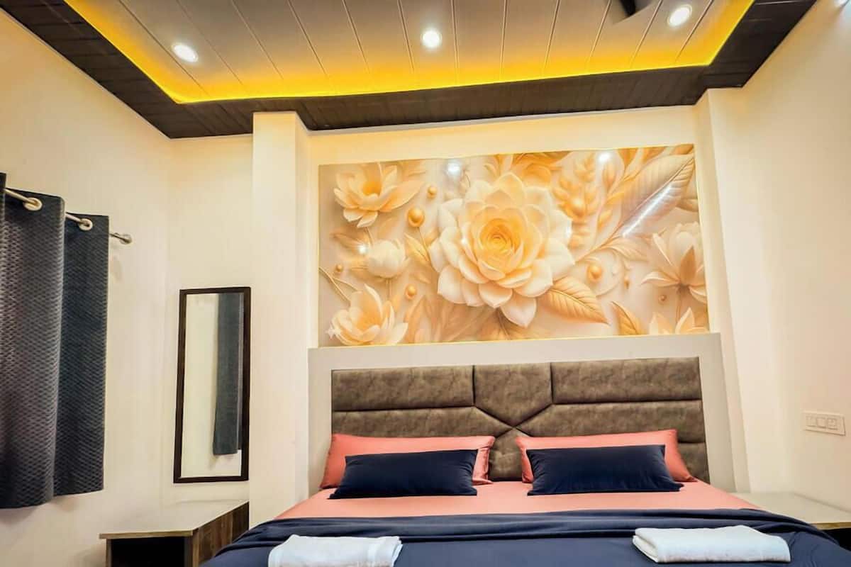 Quarto com cama grande, cabeceira com mural floral e mesa de cabeceira.