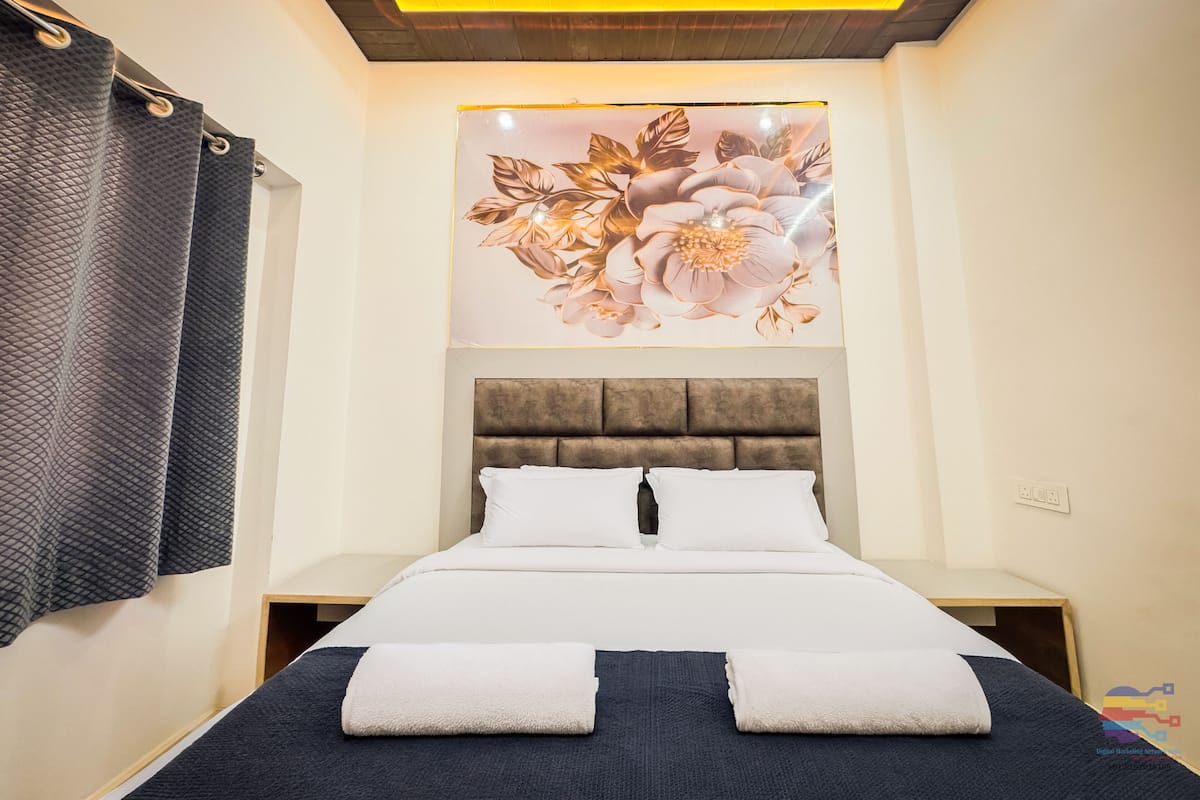 Quarto de hotel com cama, cabeceira, obra de arte na parede e luminária de teto.