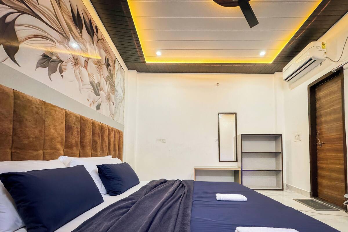 Quarto de hotel com cama, mesa de cabeceira, guarda-roupa e ventoinha no teto.