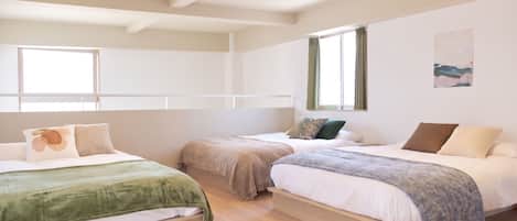 Quarto moderno com duas camas, uma janela grande e um quadro na parede.