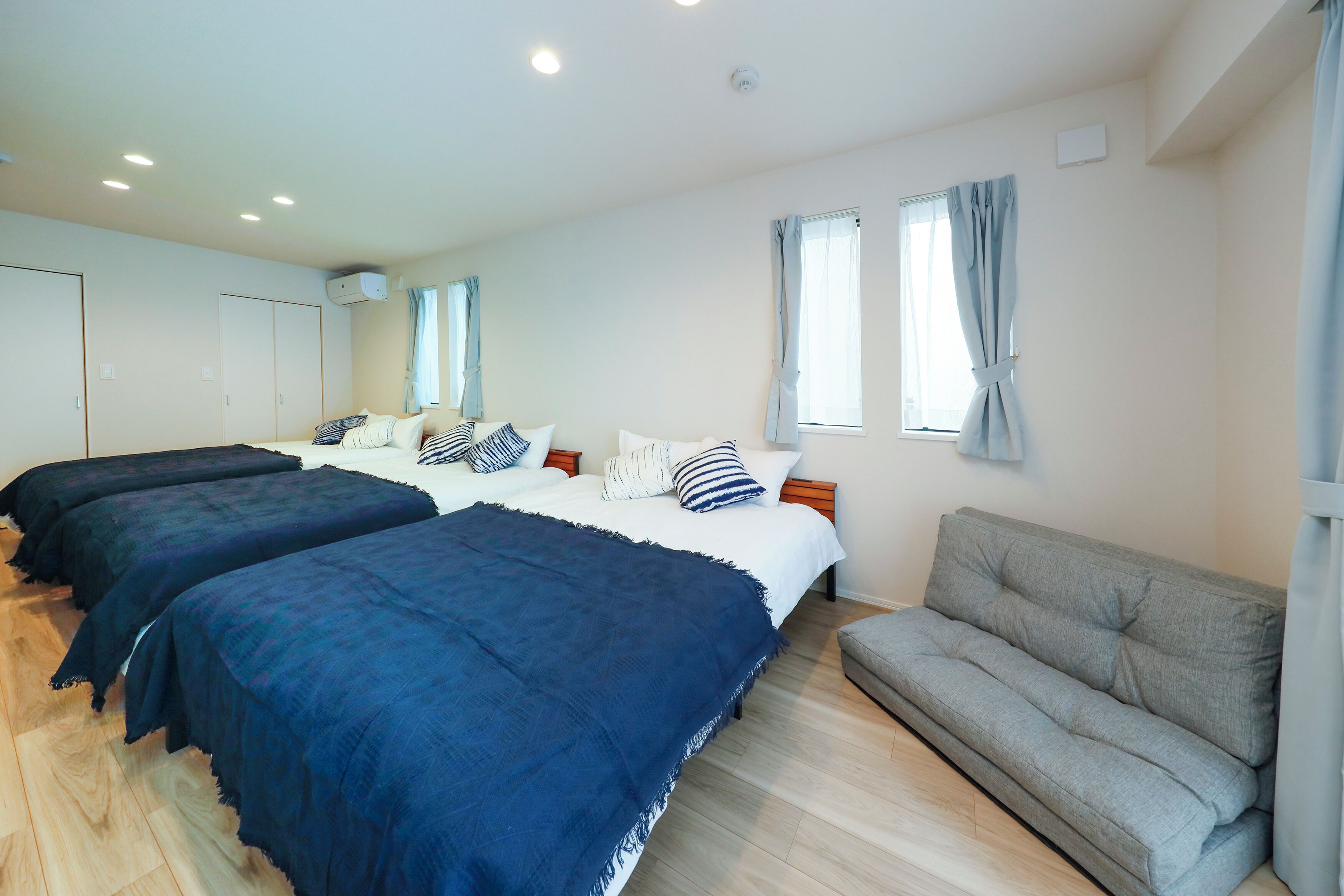 Quarto de hotel com duas camas, um sofá e uma janela com cortinas.