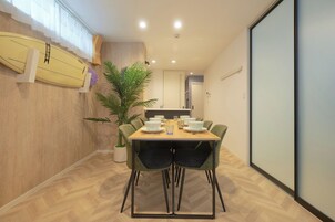 Uma área de refeições com uma mesa de madeira, cadeiras e uma prancha de surf na parede.