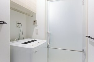 Uma área de lavanderia com máquina de lavar, tomada e porta.