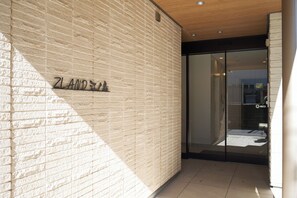 Entrada de um edifício com parede de tijolos e porta de vidro.