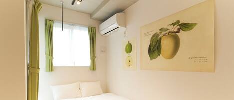 Quarto com cama, ar condicionado, janela com cortinas e duas pinturas penduradas na parede.