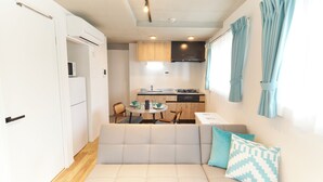 Um espaço compacto com cozinha compacta, sofá com almofadas e área de refeições.