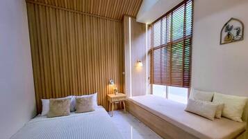 Quarto com cama, mesa de cabeceira, banquinho e janela com persianas.