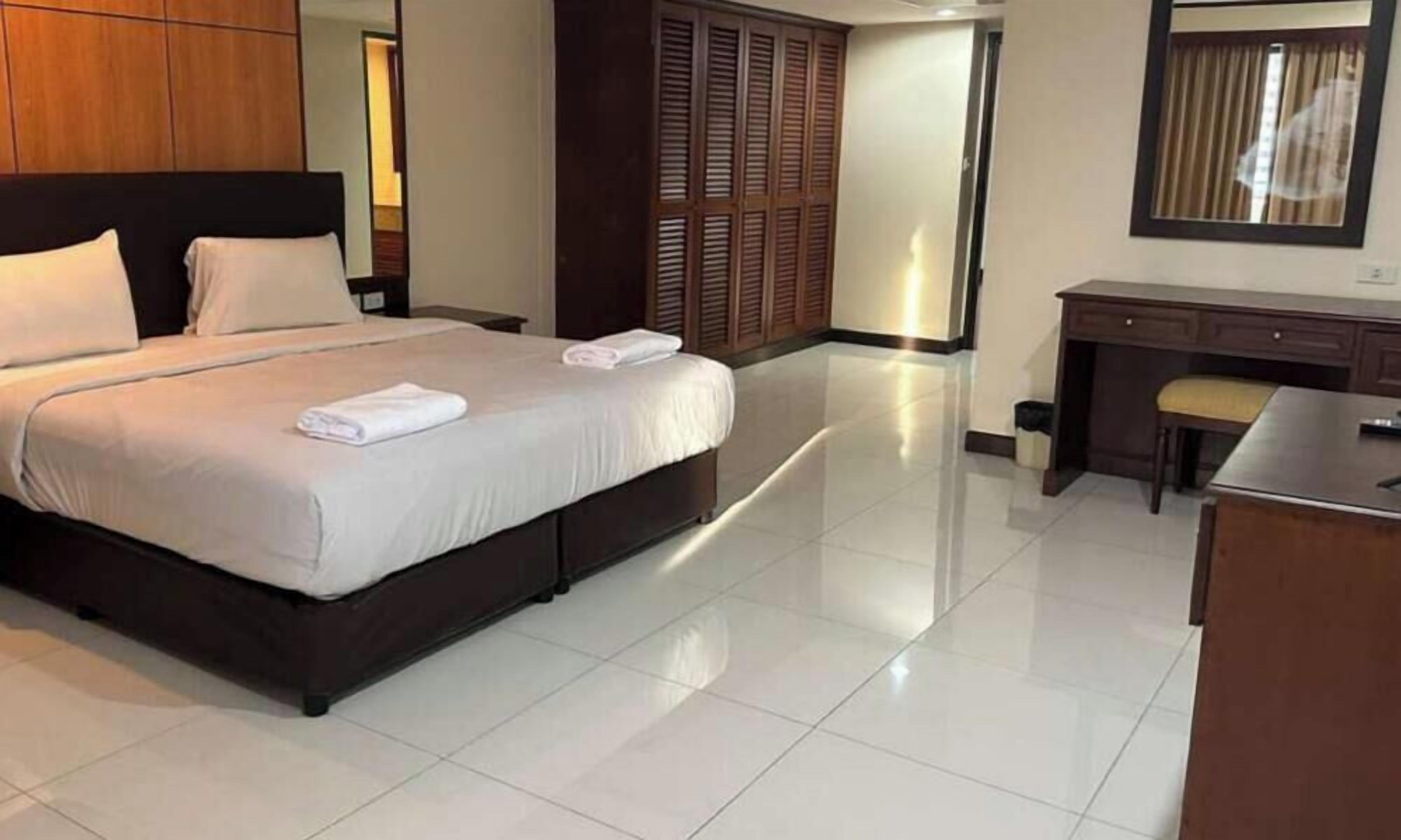 Quarto de hotel com cama, escrivaninha, cadeira e guarda-roupa.