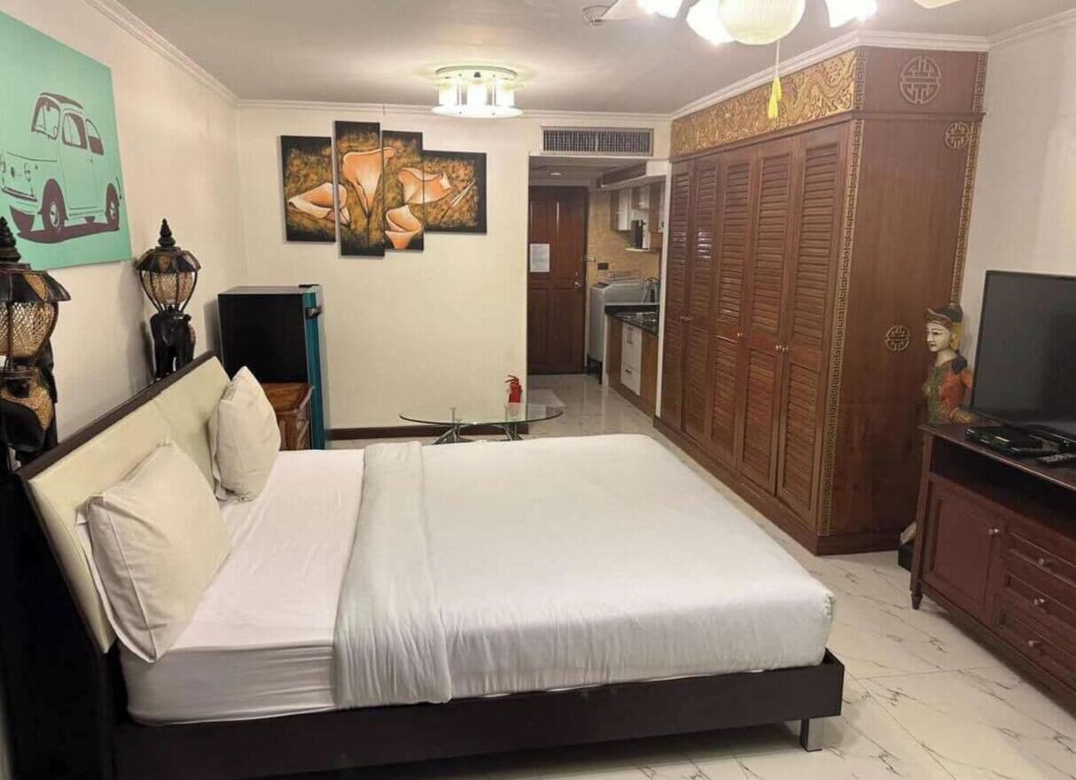 Quarto com cama, escrivaninha, guarda-roupa e televisão.