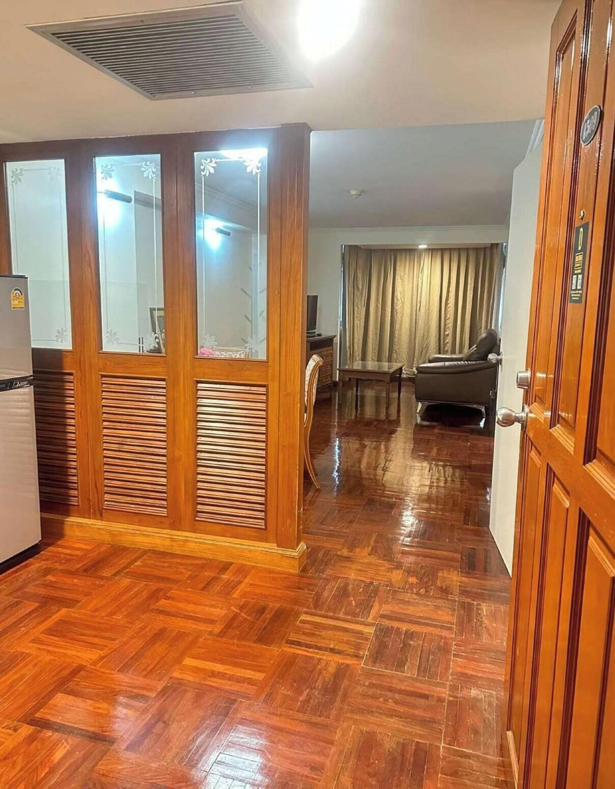 Quarto com piso de madeira, sofá, mesa e televisão.