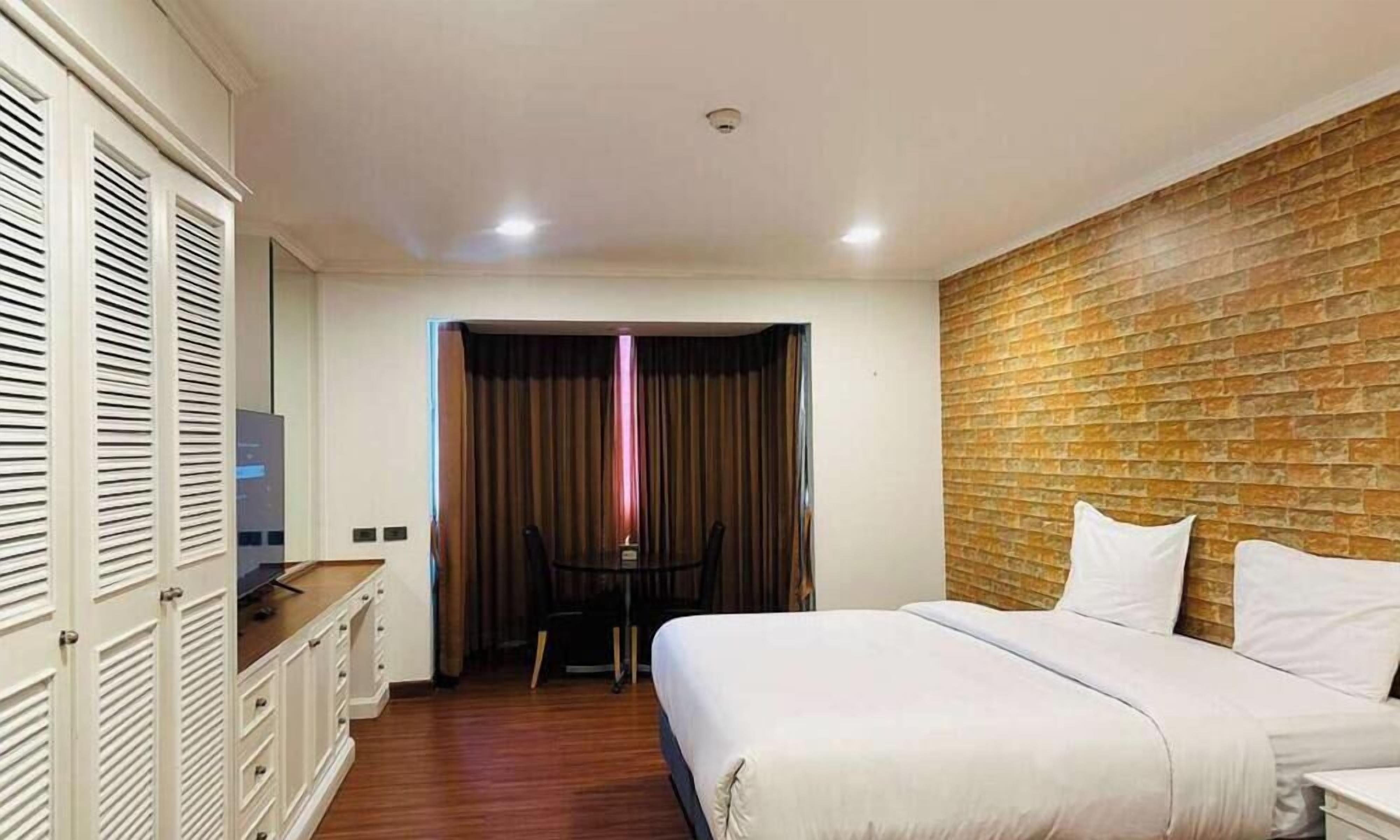 Quarto de hotel com cama, escrivaninha e armário.