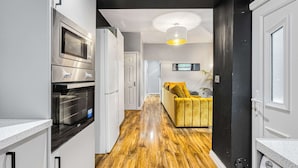 Uma cozinha moderna com eletrodomésticos embutidos, piso de madeira e um sofá amarelo na sala de estar.