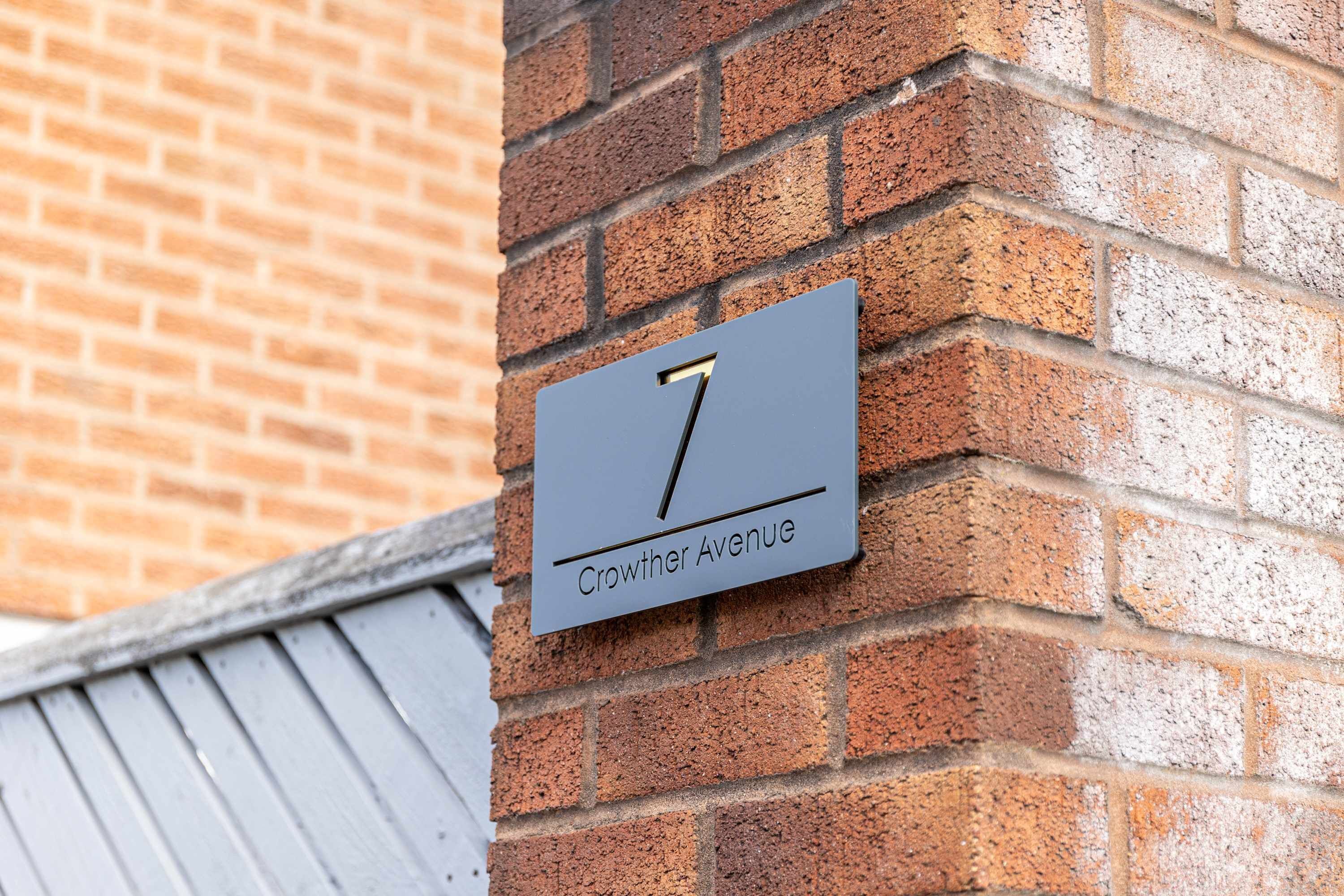 Placa com o número da casa numa parede de tijolos.