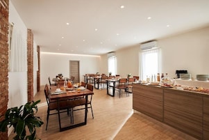 Uma área de refeições moderna com mesas e cadeiras de madeira, um balcão de buffet e uma parede de tijolos.