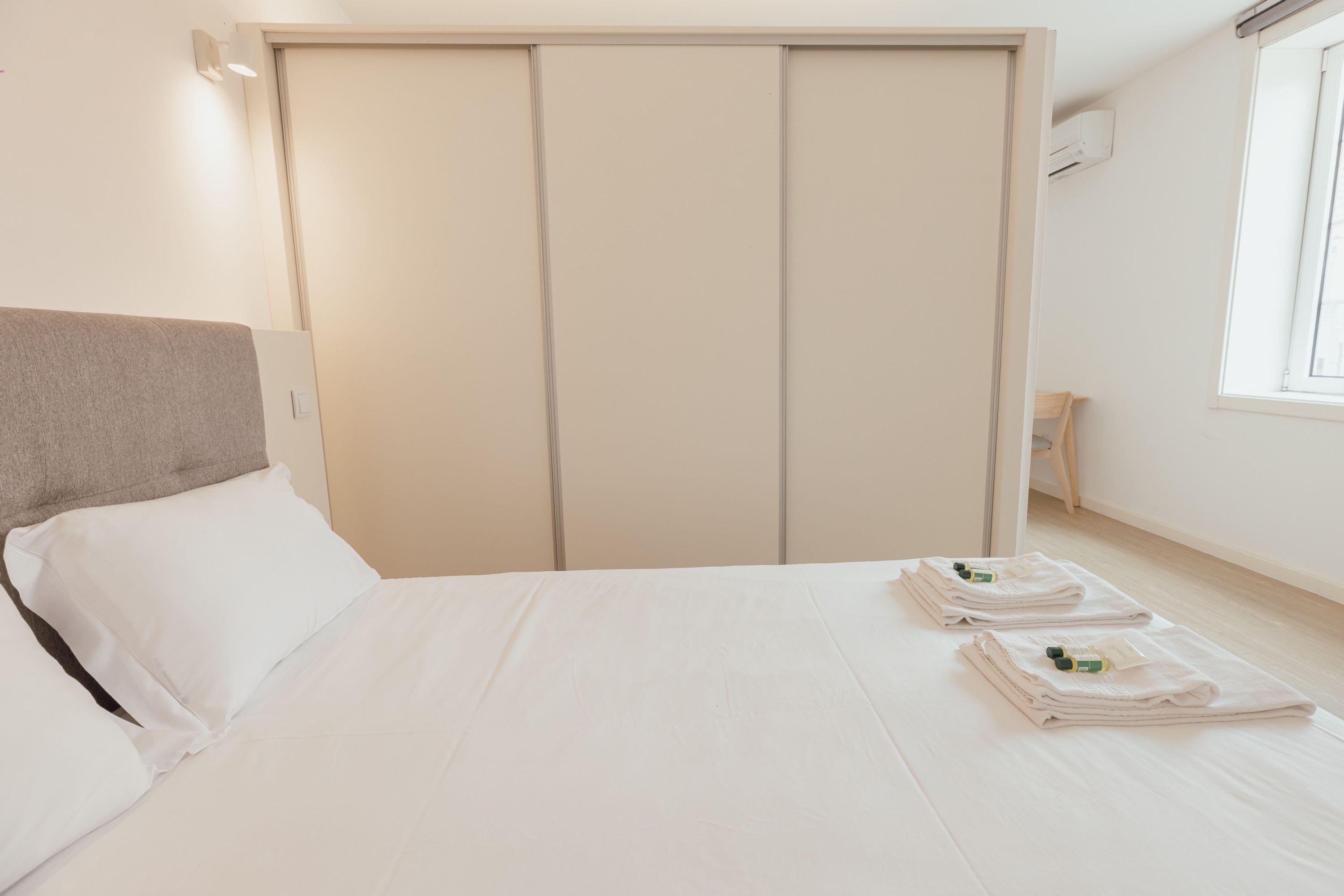 Quarto de hotel com cama, guarda-roupa e janela.