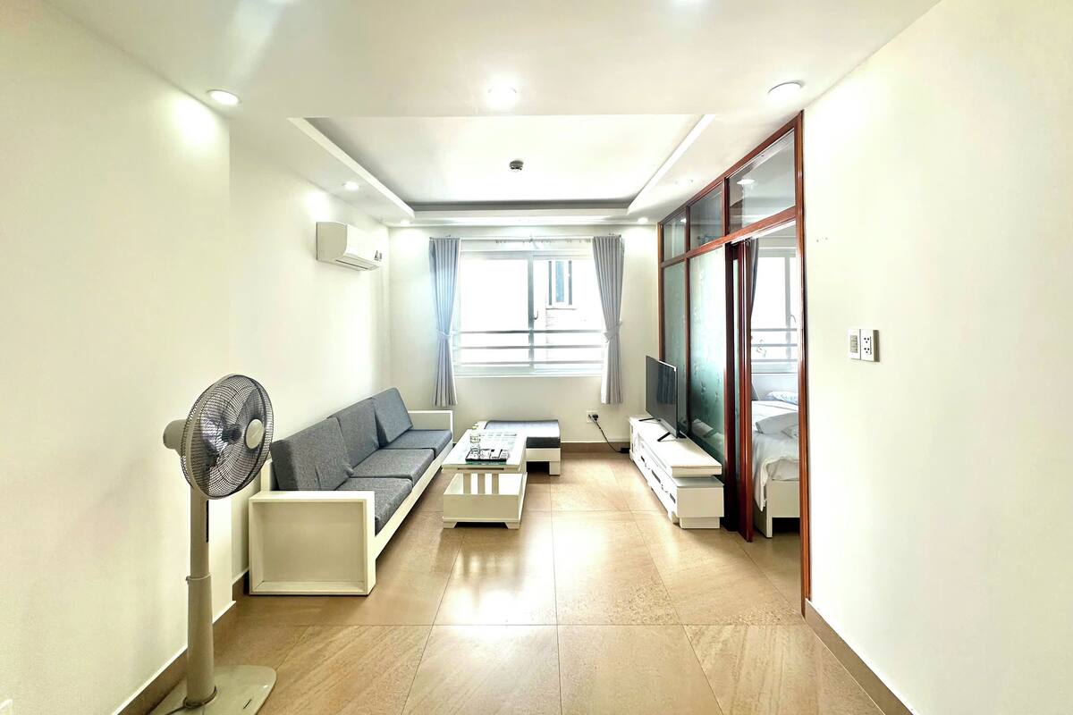 Uma sala de estar moderna com um sofá, mesa de centro, televisão e um ventilador.
