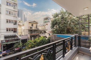 Varanda residencial com vista para prédios e uma árvore ao redor.