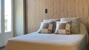 Um quarto com uma cama grande, uma parede de ripas de madeira e uma janela.