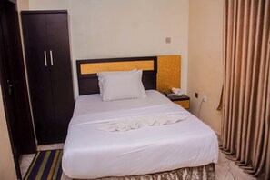 Quarto de hotel com cama, guarda-roupa, telefone e cortina.