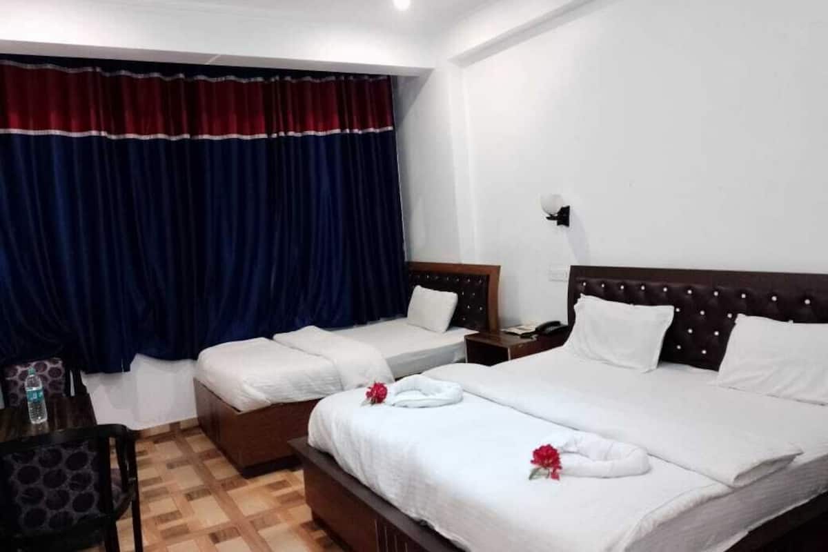 Quarto de hotel com duas camas, uma escrivaninha, uma cadeira e uma mesa de cabeceira.