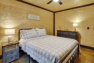 Um quarto com cama, mesas de cabeceira, cômoda e ventilador de teto.