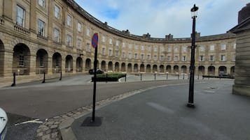 Um edifício histórico com fachada curva, janelas em arco e um pátio central.