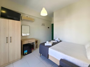 Quarto com cama, escrivaninha, espelho, guarda-roupa e televisão.