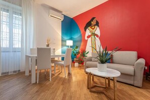 Uma sala de estar moderna com área de jantar, parede em vermelho e um sofá.