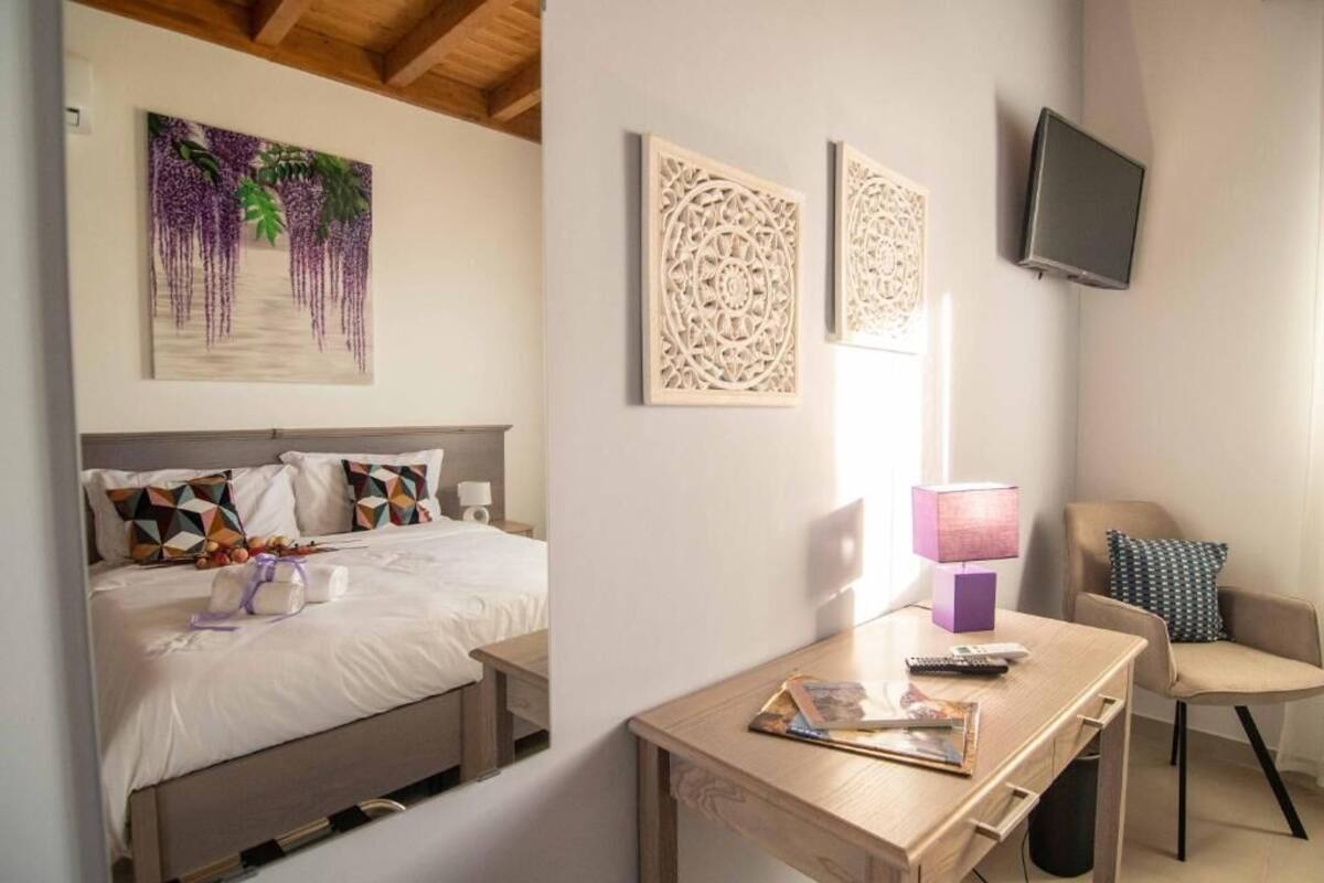 Quarto de hotel com cama, escrivaninha, televisão e obras de arte nas paredes.