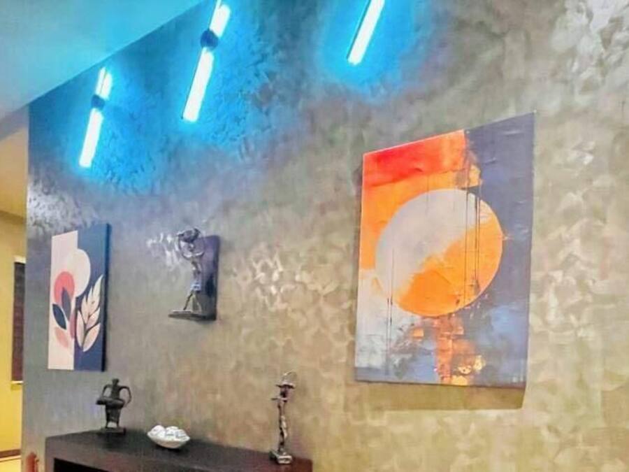 Quarto com parede texturizada, balcão de recepção e obras de arte.