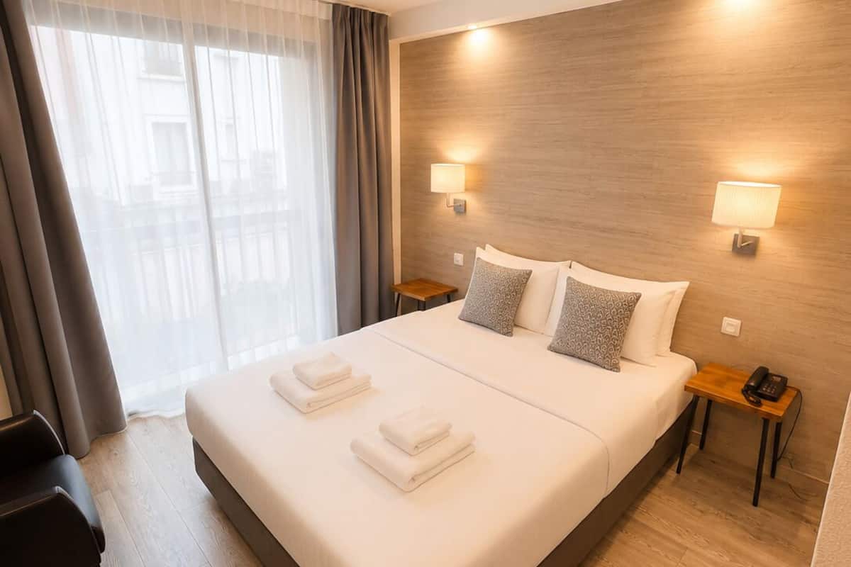 Quarto de hotel com uma cama grande, duas mesas de cabeceira, uma escrivaninha e uma cadeira.
