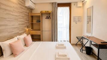 Quarto de hotel com uma cama grande, uma escrivaninha, um guarda-roupa e um espelho.