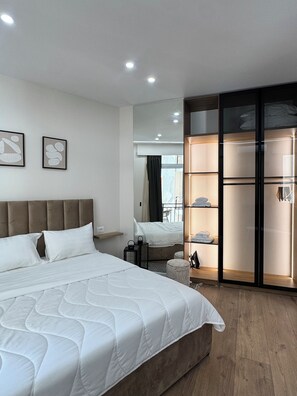 Quarto de hotel moderno com uma cama grande, um guarda-roupa com portas deslizantes e vista para a varanda.