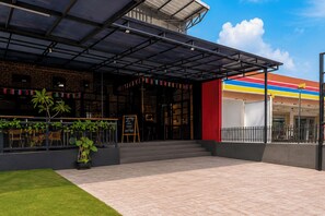 Um edifício moderno com área de estar coberta ao ar livre, fachada de tijolos e uma vitrine colorida ao fundo.