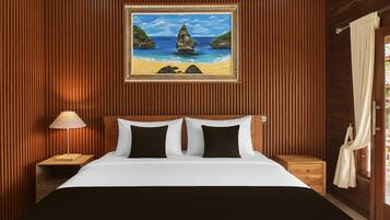 Quarto de hotel com cama, mesa de cabeceira, abajur, pintura de uma cena de praia e janela com cortinas.